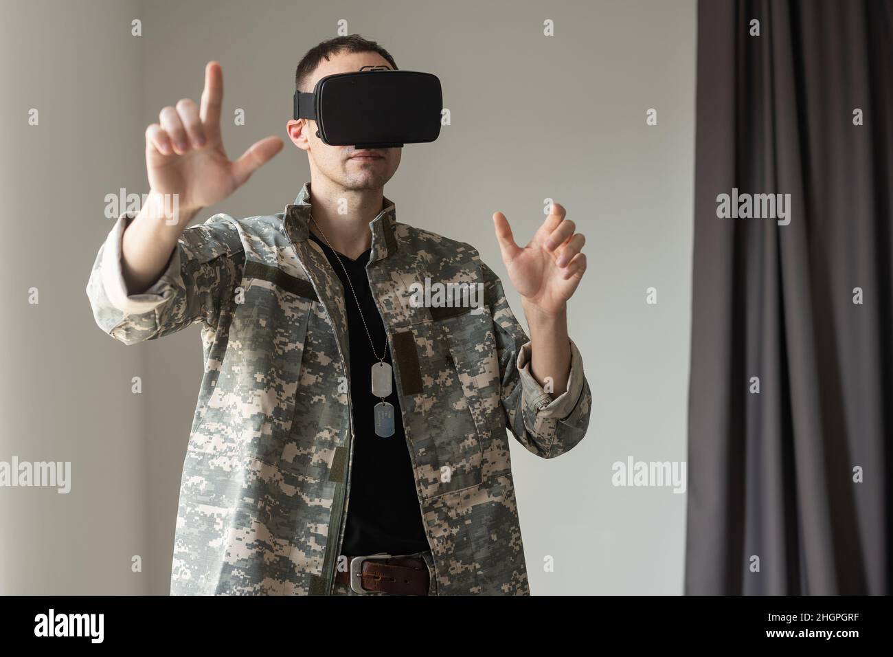 Military man trying to touch virtual objects while wearing a VR headset ...