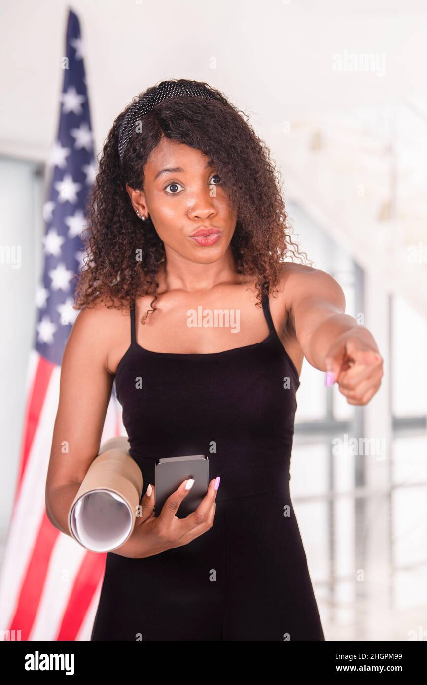 African American woman holding mobile, paperwork and pointing at the ...