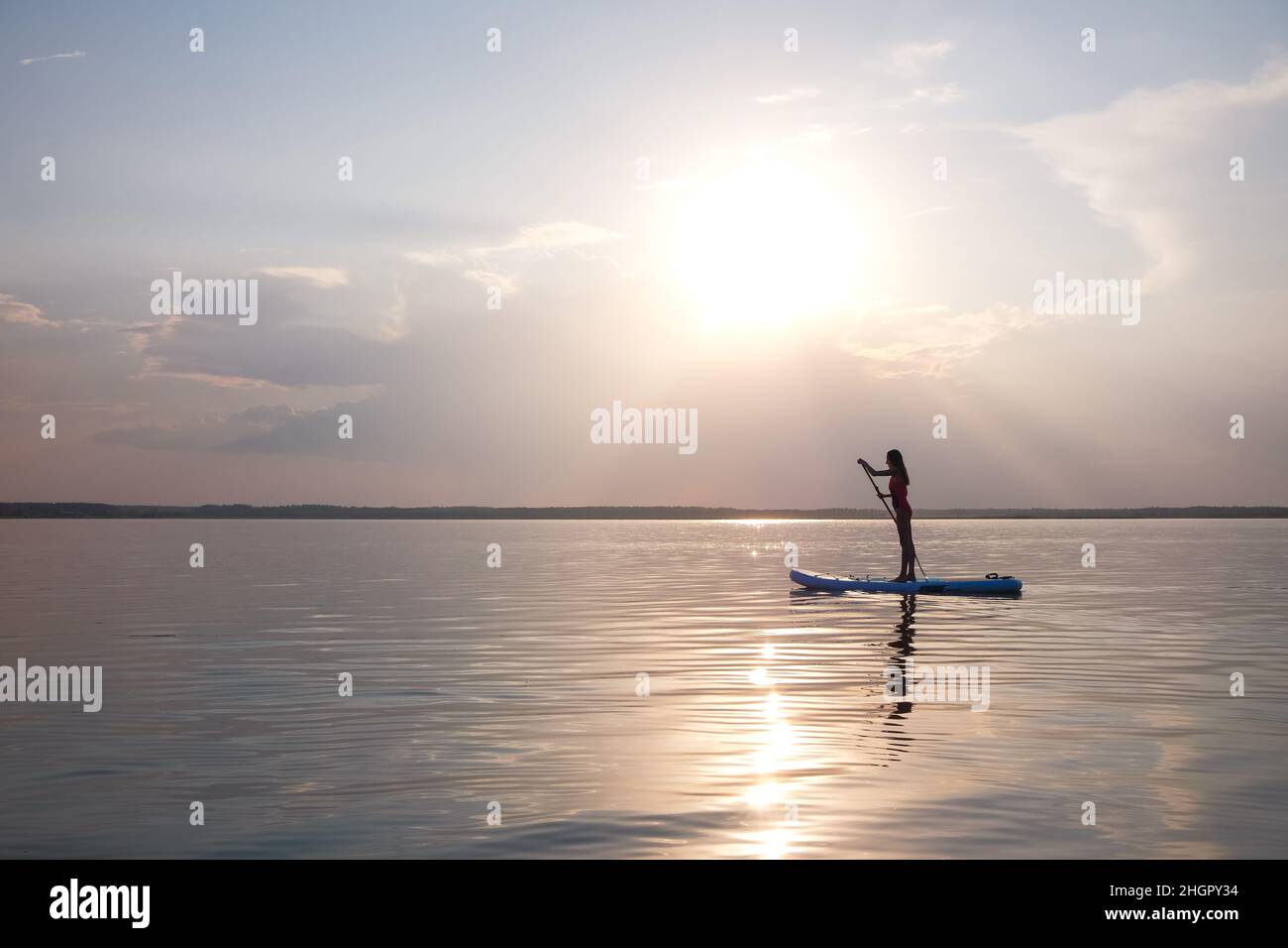 Silhouette of young female paddle boarding at sunset Stock Photo - Alamy