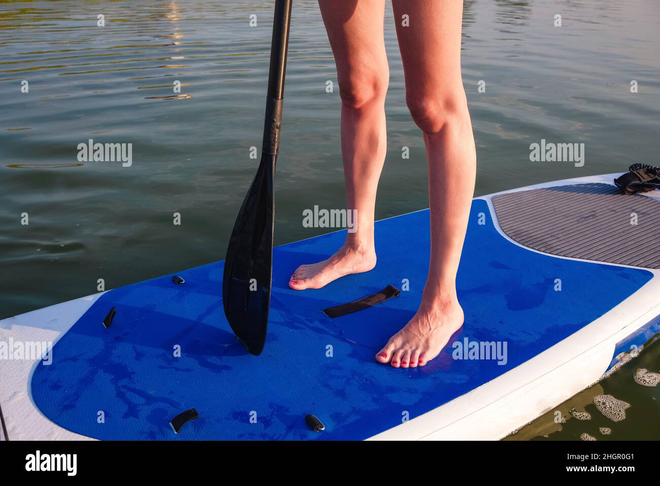 Female standing paddle boarding at sunset Stock Photo - Alamy
