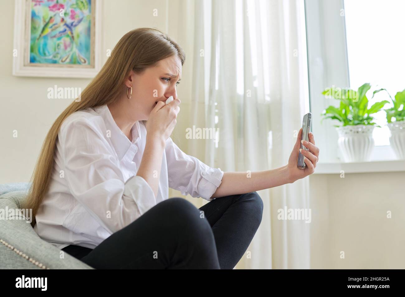 Young woman crying looking at smartphone screen Stock Photo - Alamy
