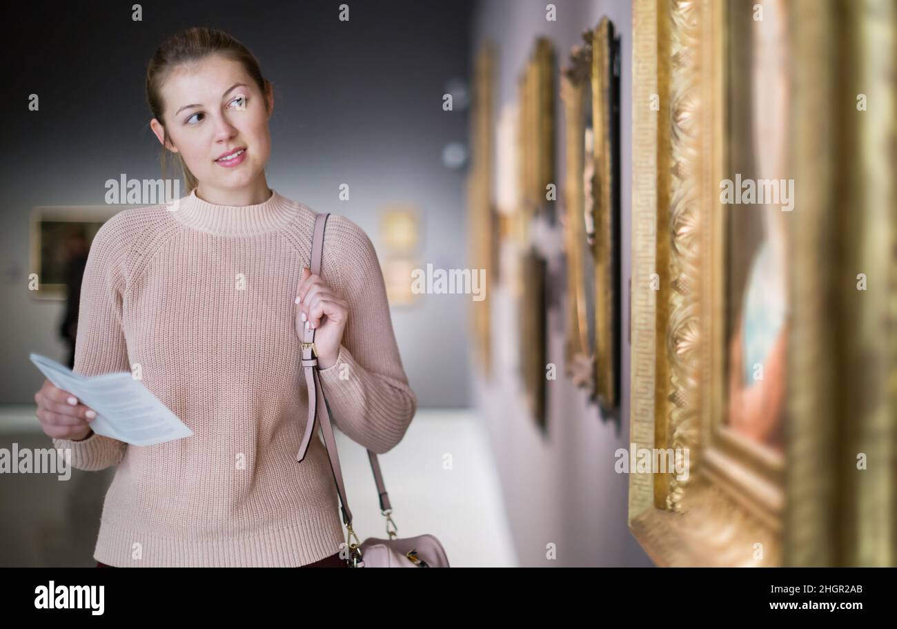 Woman with guide looking at pictures in museum Stock Photo - Alamy