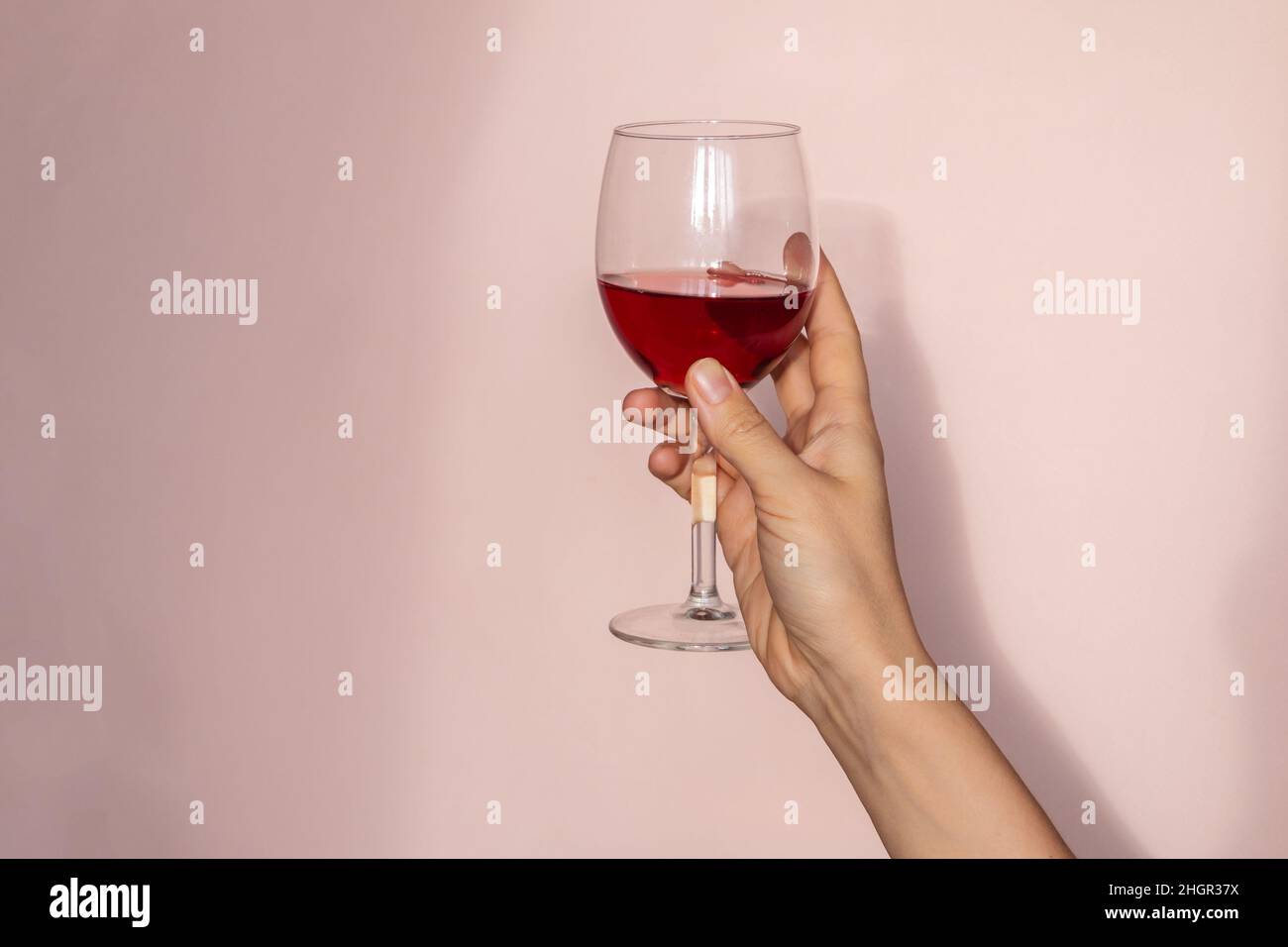 Woman hand holding glass of red wine, natural sunlight and abstract ...