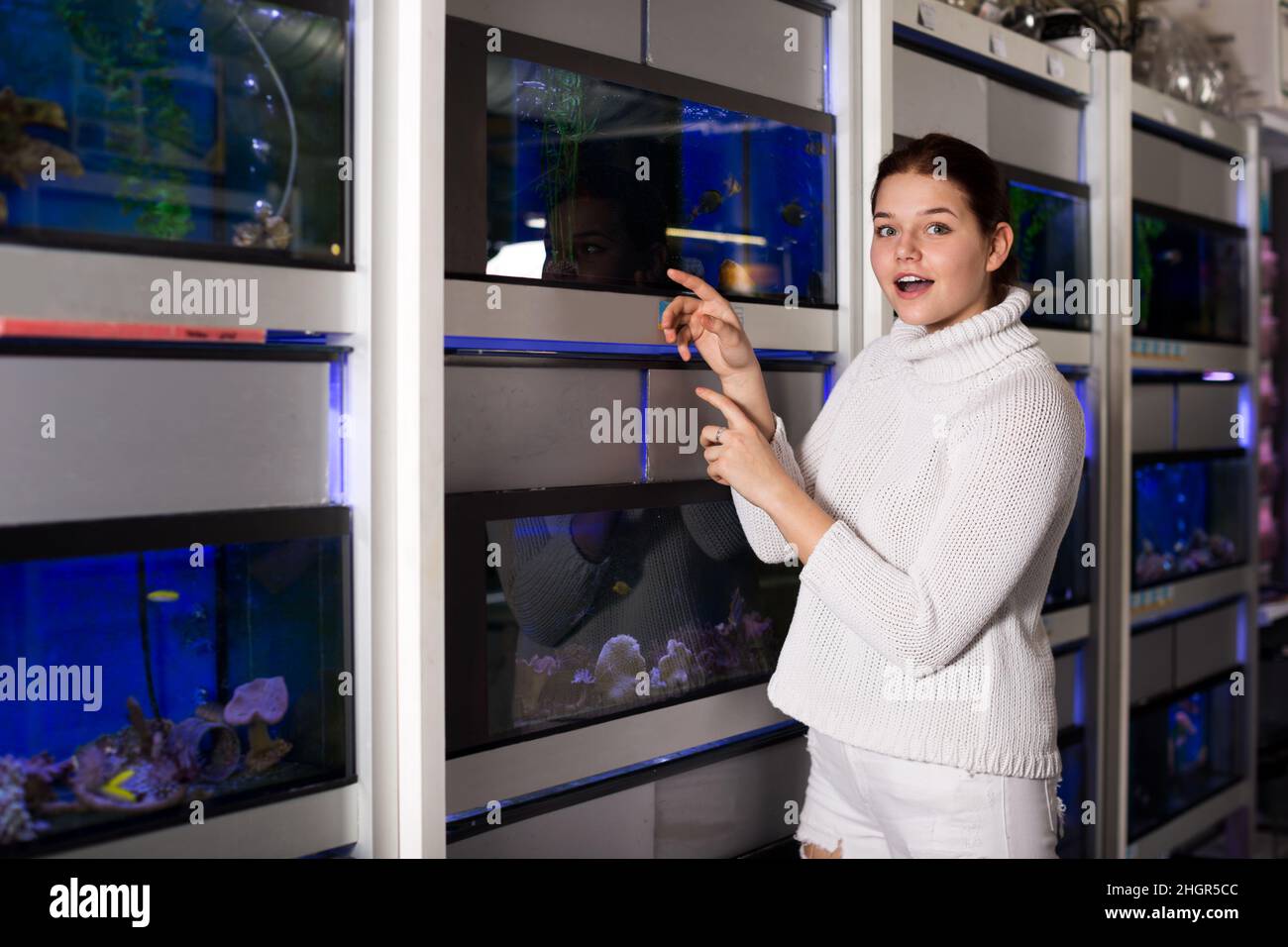 Girl in aquarium shop points to colored fish Stock Photo - Alamy