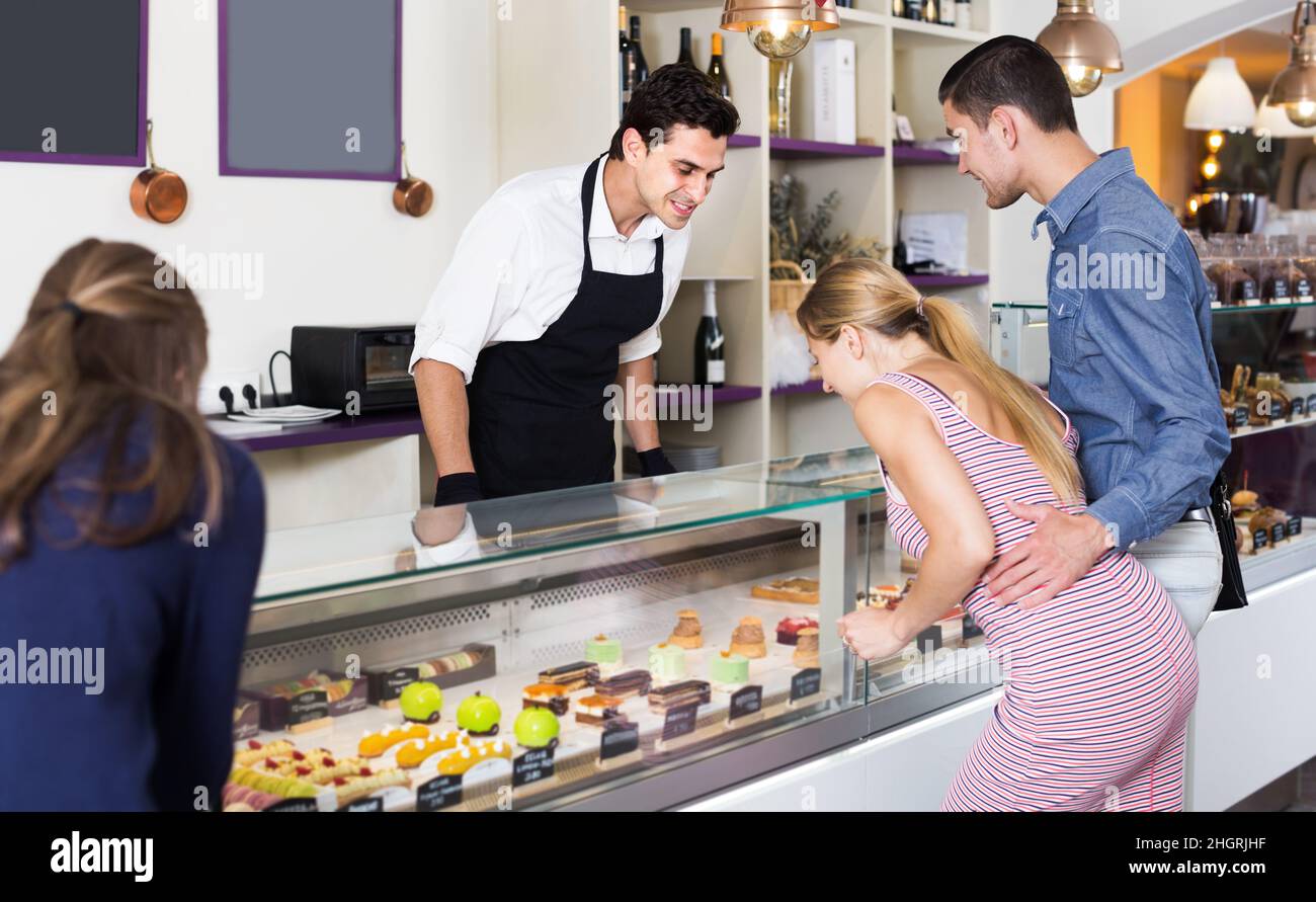 Positive man confectioner serving visitors Stock Photo - Alamy