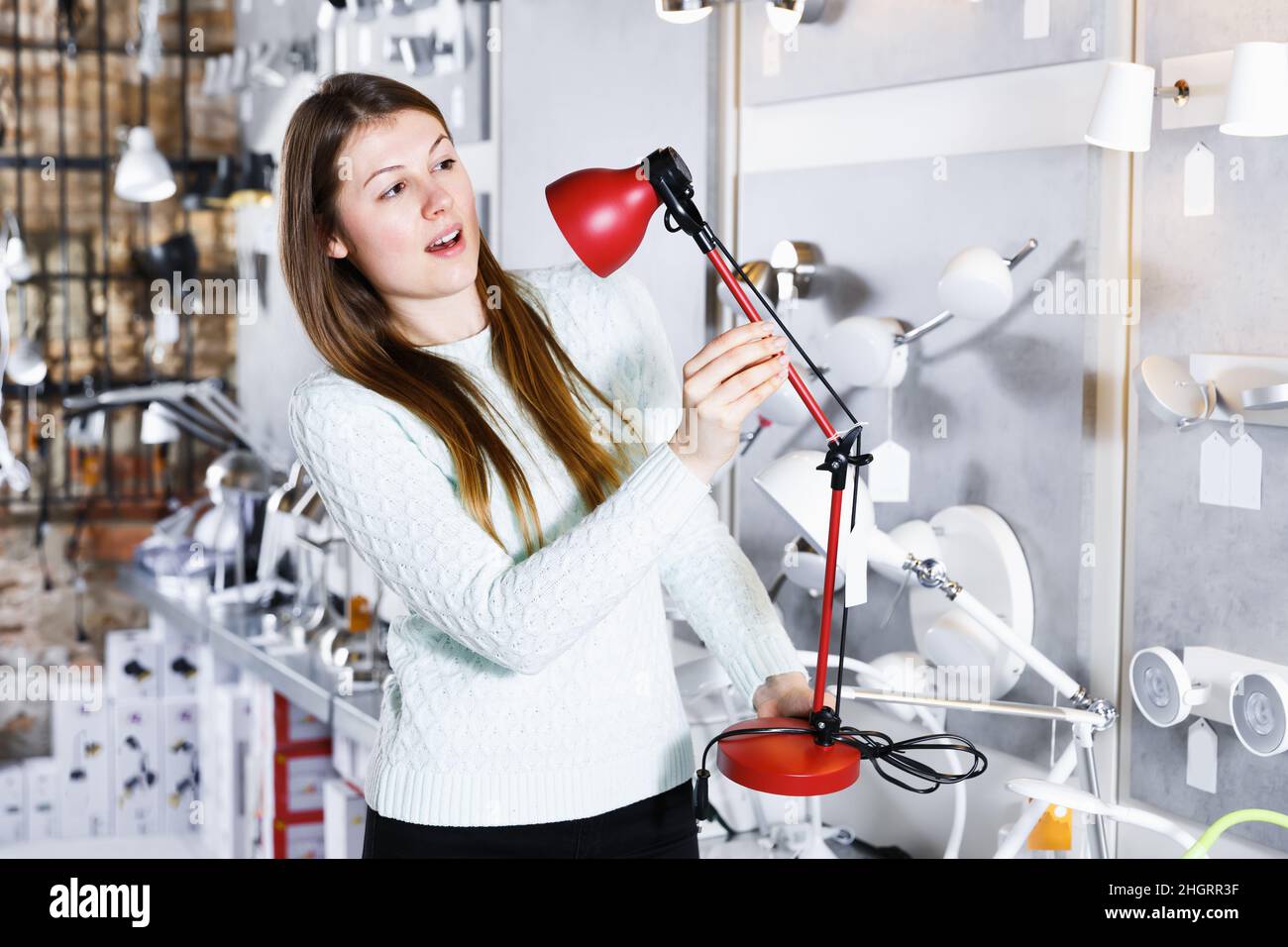 Glad woman trying to use desk lamp Stock Photo - Alamy