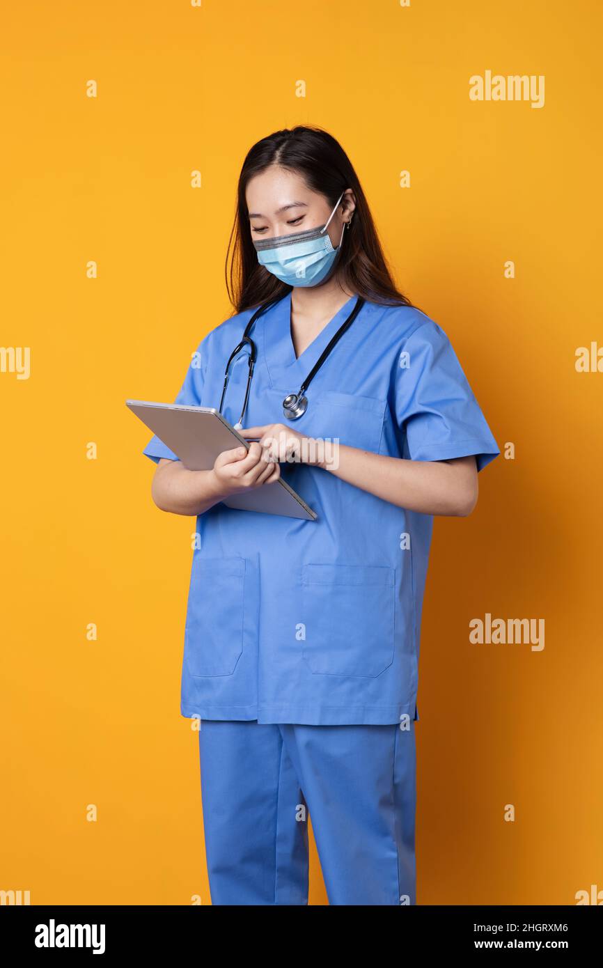 Vertical studio photo with orange background of a female doctor with ...