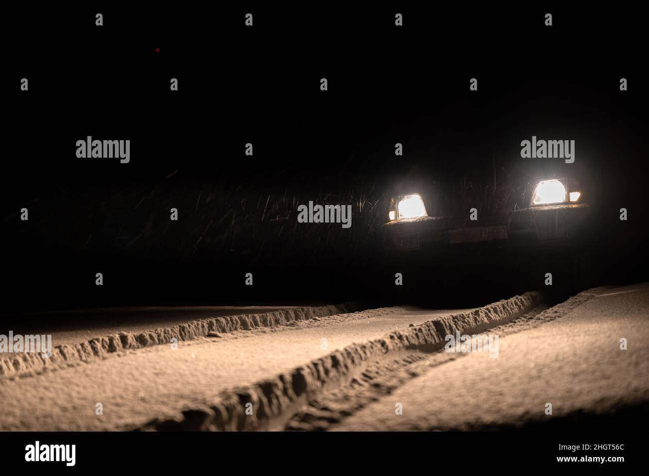 The lights of a car driving at night during a snowstorm Stock Photo - Alamy
