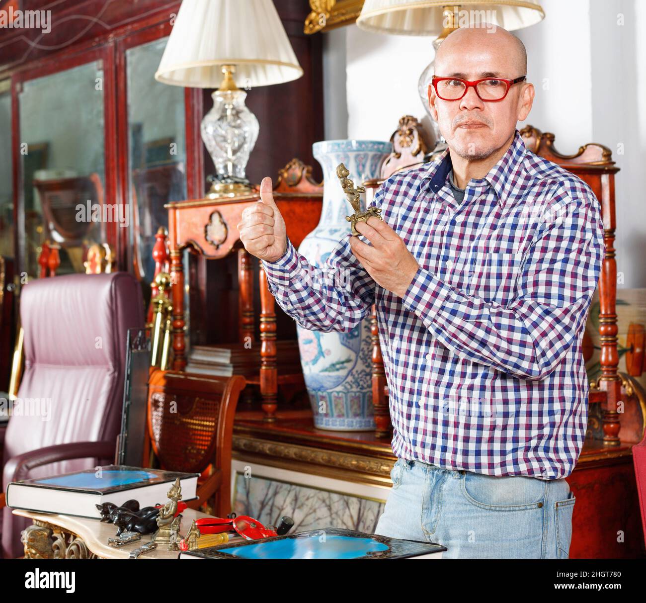 Portrait of successful owner of antiques shop among vintage things ...