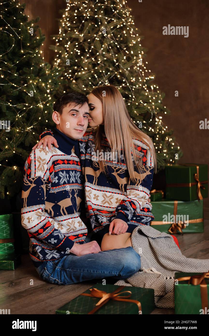 A guy and a girl hug and kiss against the background of a Christmas ...