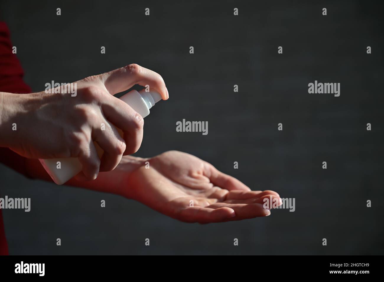 Female hands applying alcohol antibacterial spray to prevent the spread ...