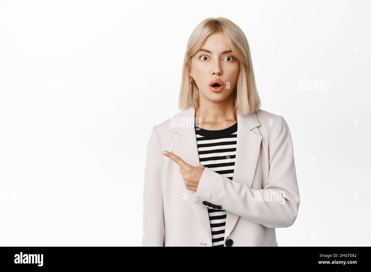 Image of businesswoman with surprised face, pointing finger left at ...