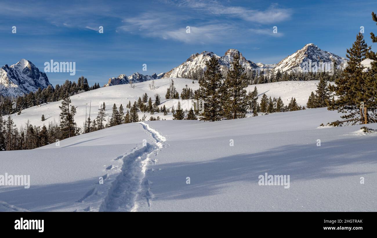 Tracks in the snow lead to the high rocky mountains of Idaho Sawtooths ...