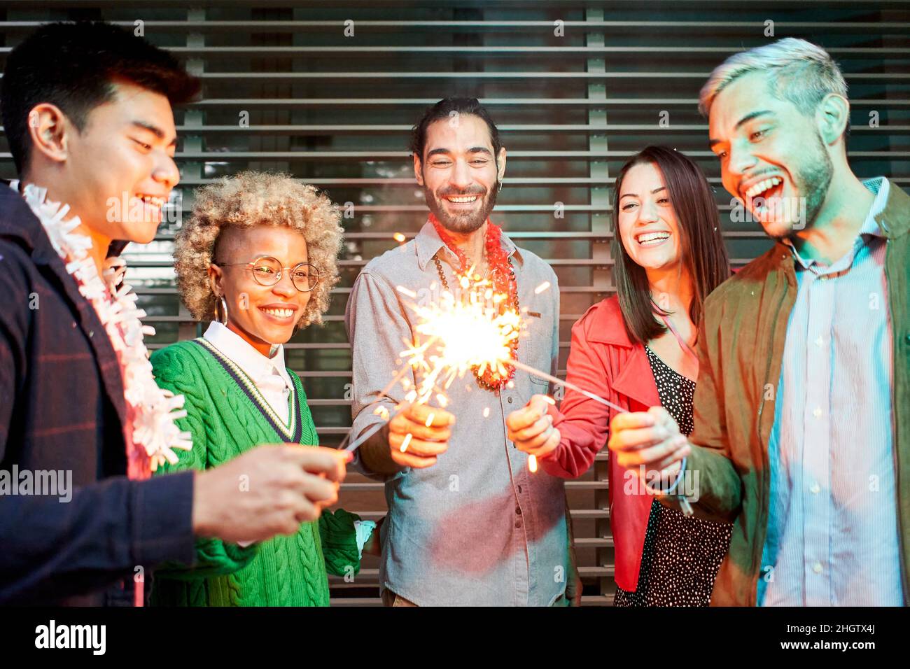 Multi-ethnic millennial group of friends folding sparklers Stock Photo ...