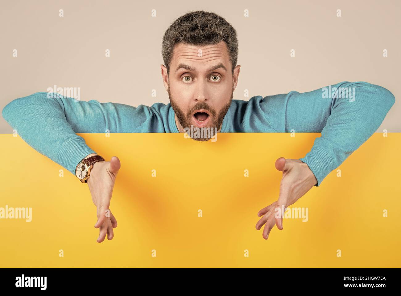 surprised man behind blank paper banner with copy space for information ...
