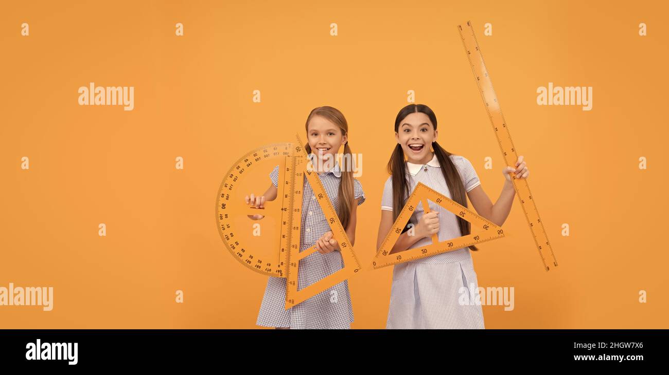 Happy teen girls hold geometric tools for geometry lesson orange ...