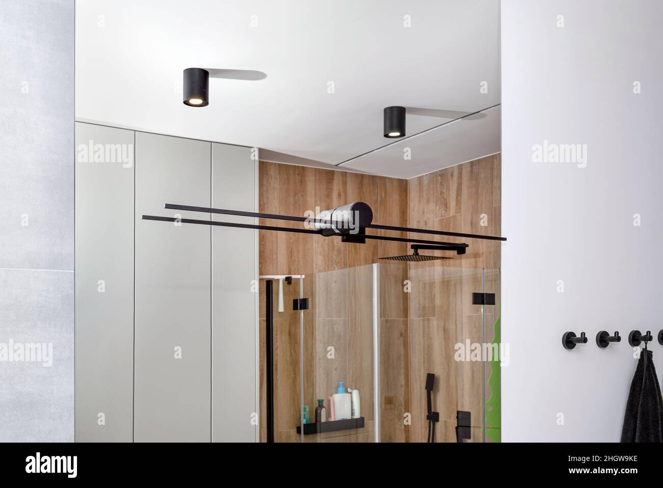 Black sconce mounted in a large mirror in the bathroom, visible LED ...