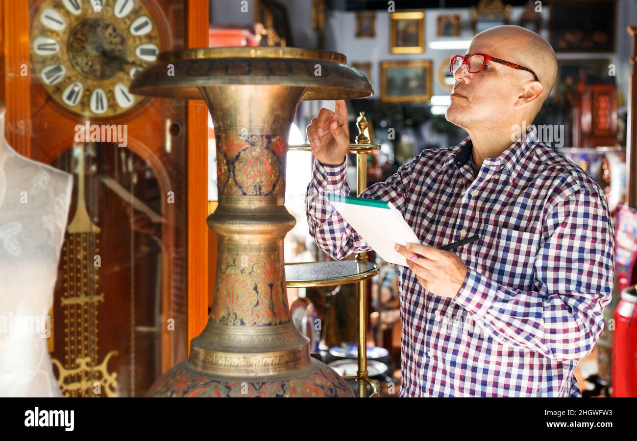 Man making notes in antique store Stock Photo - Alamy