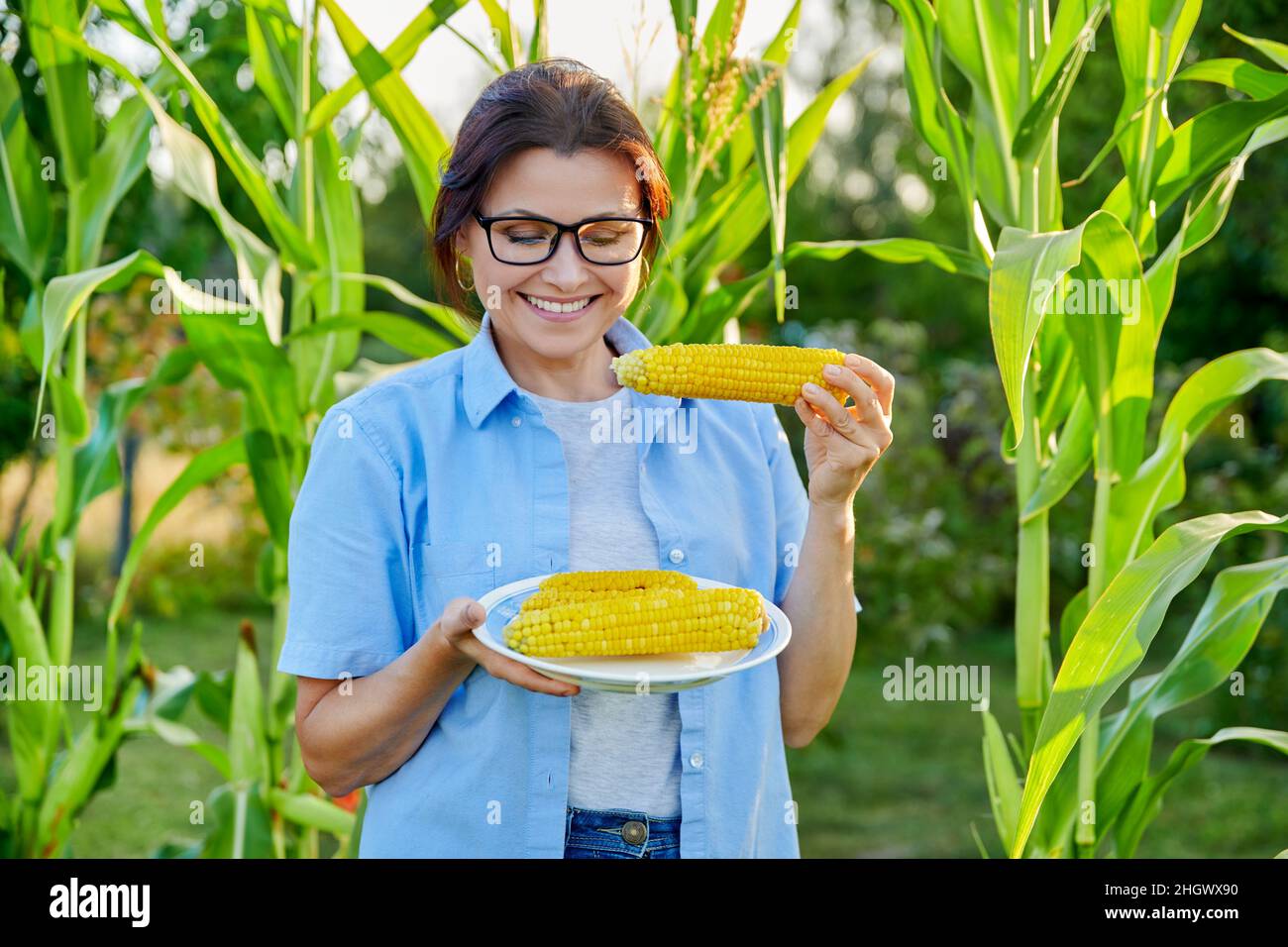 Smiling middle aged woman eating boiled ripe corn on the cob Stock ...