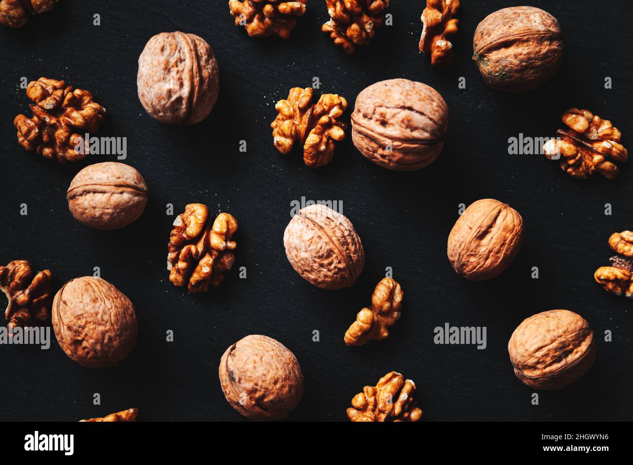 Whole and peeled walnuts on a black background. Close-up, flat lay, top ...