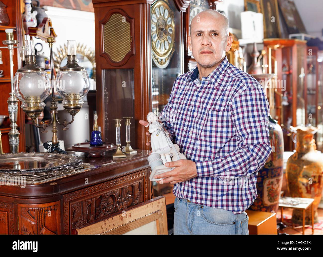 Portrait of successful owner of antiques shop among vintage things ...