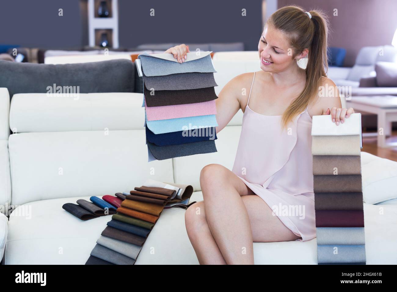 Glad woman touching color textile for sofa Stock Photo - Alamy