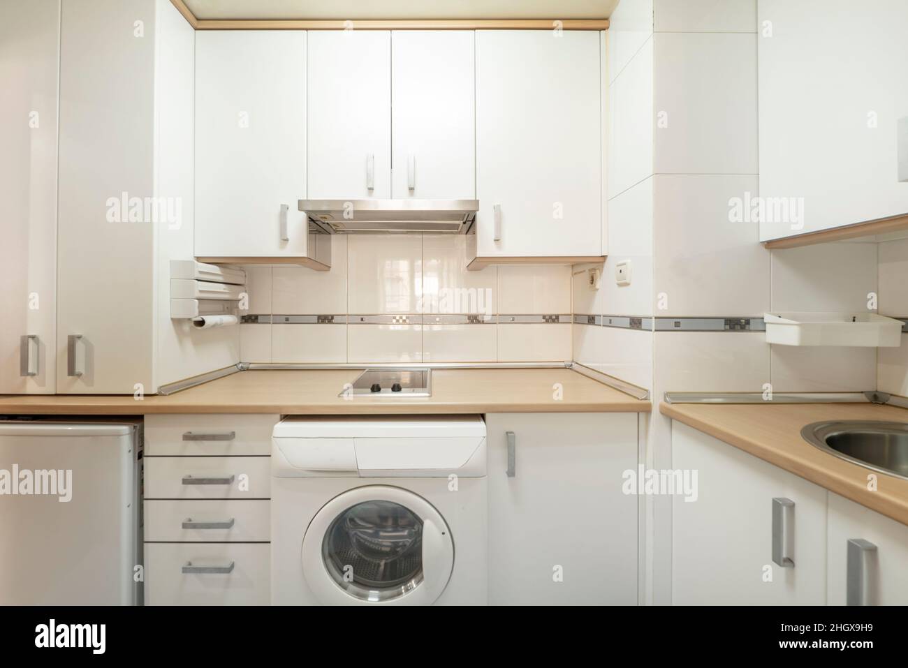 Kitchenette with light wood countertops and white cabinets with ...