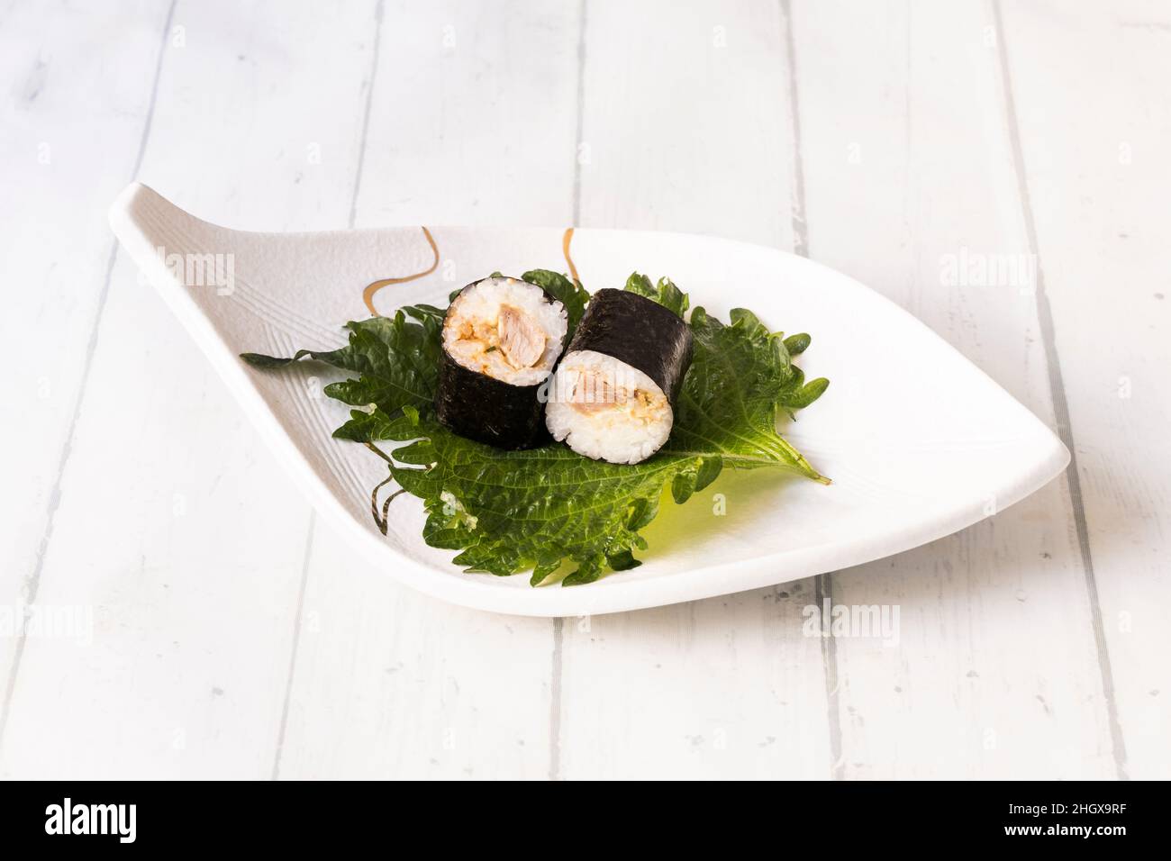 Boiled tuna maki with teriyaki sauce rolled in nori seaweed on a shiso ...