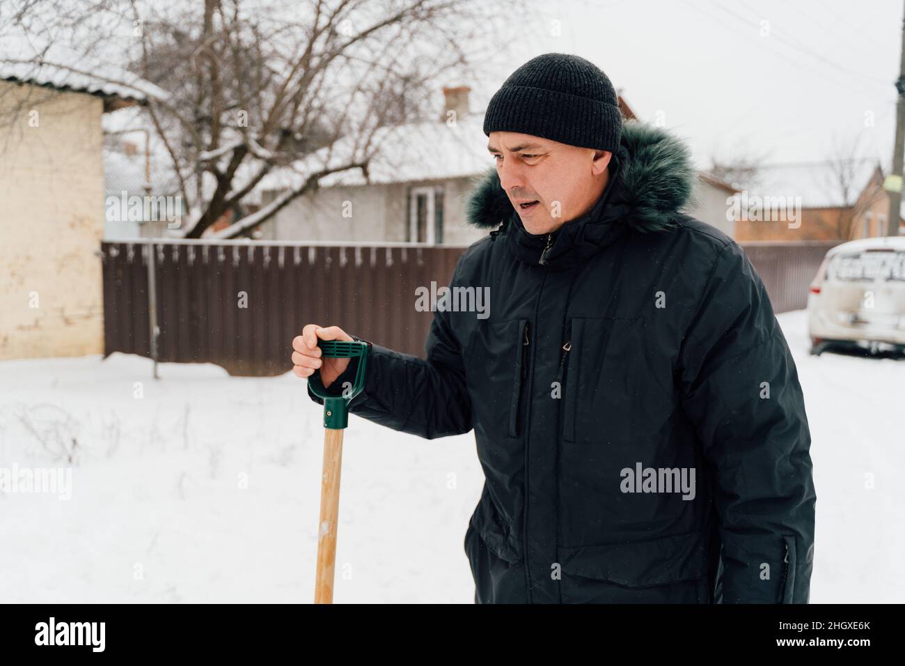 Snow collapse. Senior man cleaning snow at winter weather with a shovel ...