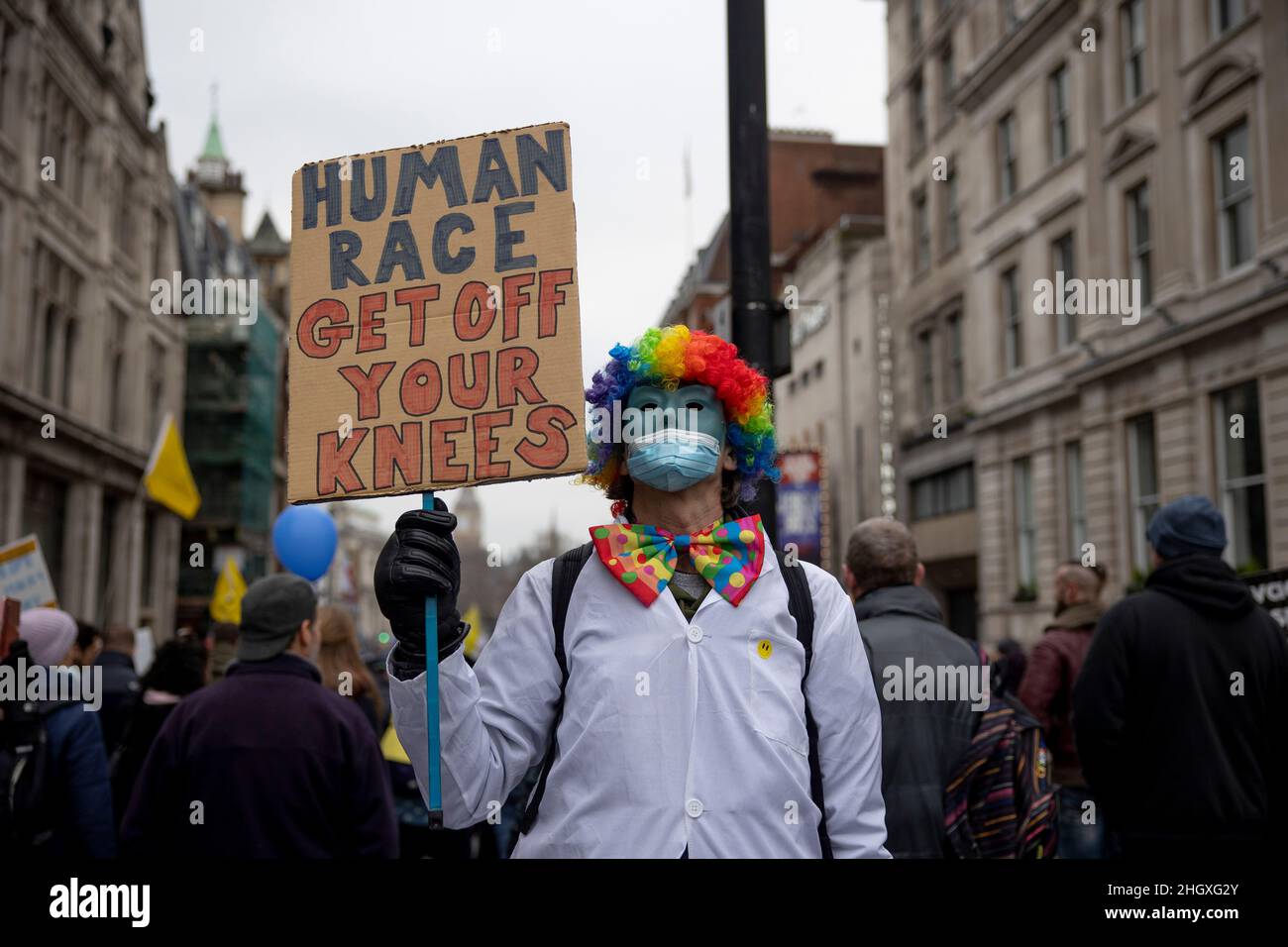 A man dressed as a clown scientist holds a placard during the ...