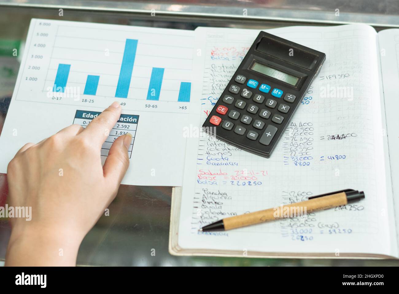 top view of a girl's hand pointing to her business statistics chart ...
