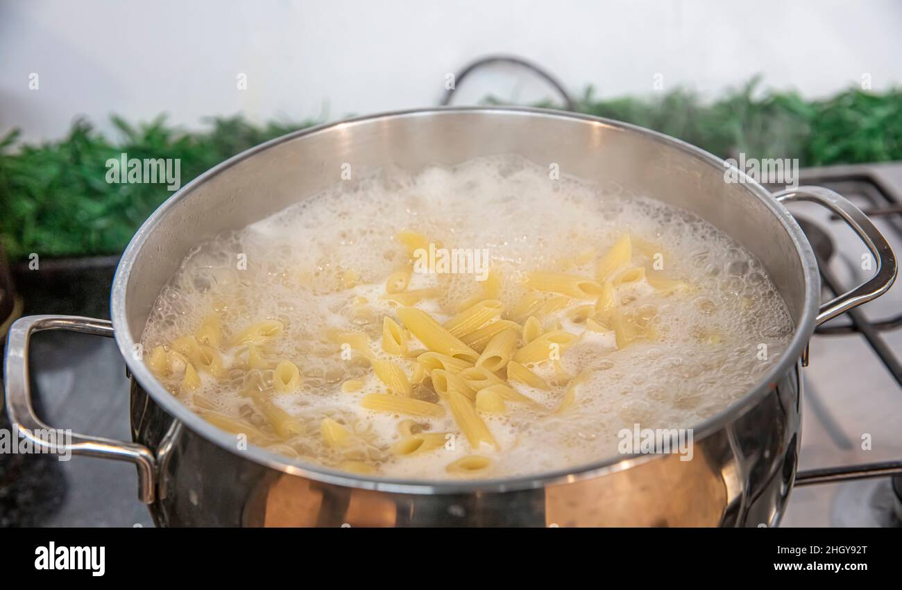 Cooking Pasta pour the penne pasta into a metal pot of boiling water ...