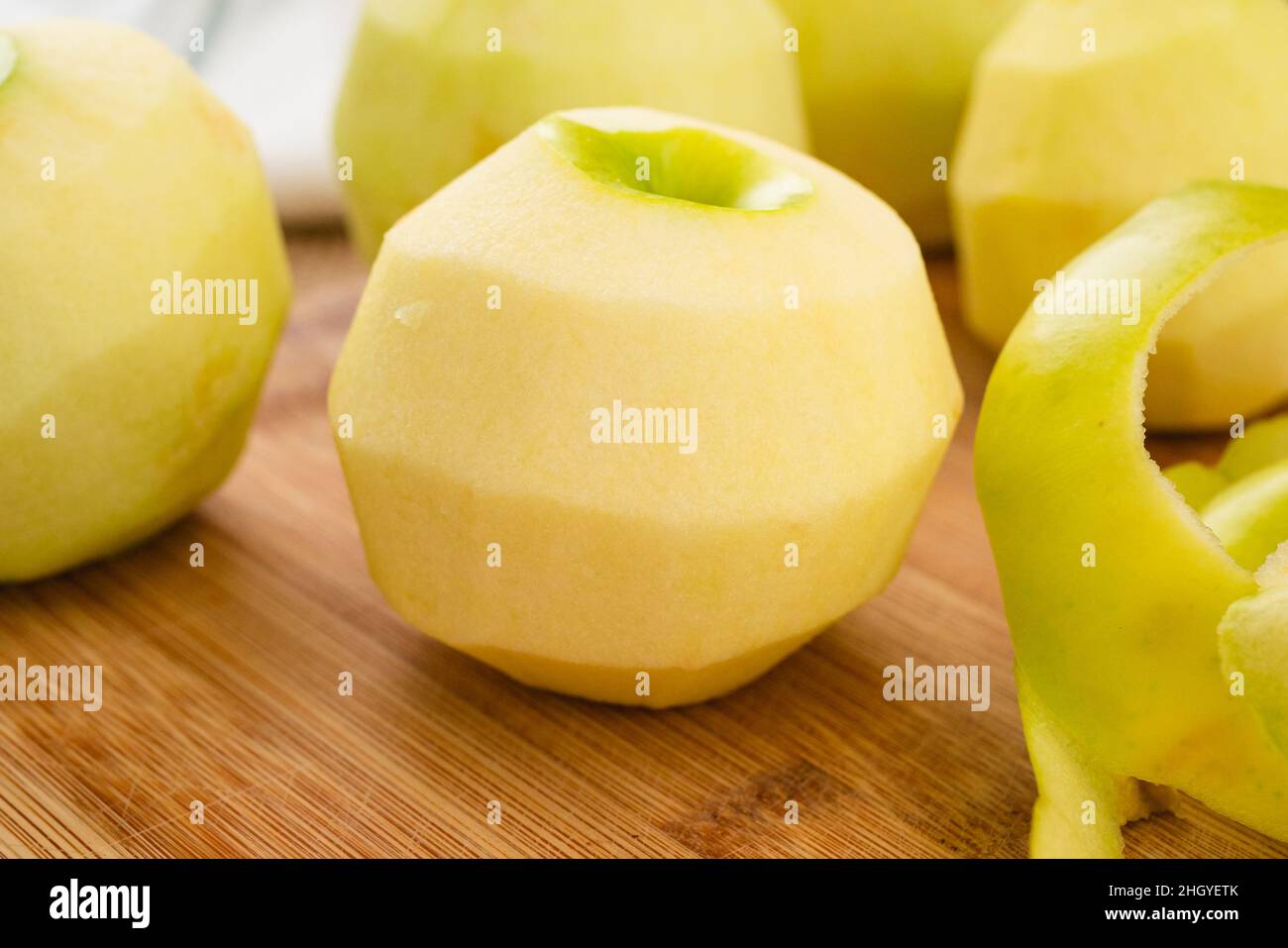 Peeled green apples close up on a wooden board on kitchen table ...