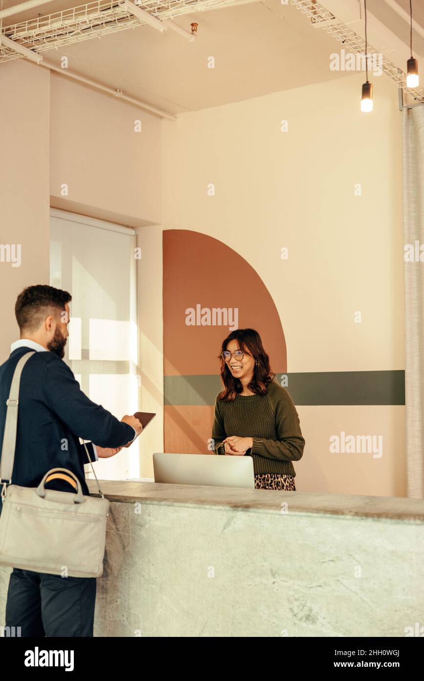 businessman signing in to an office at the front desk. Modern ...