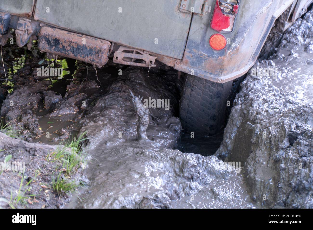 The wheel of an SUV stuck in deep mud on an impassable country road ...