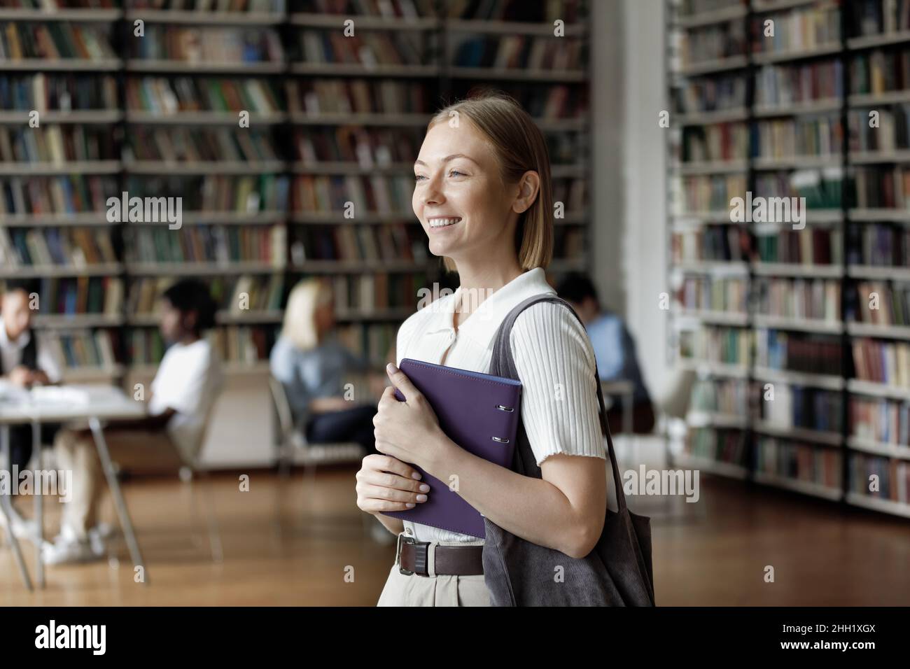 Happy pretty smart college girl walking in public university library ...