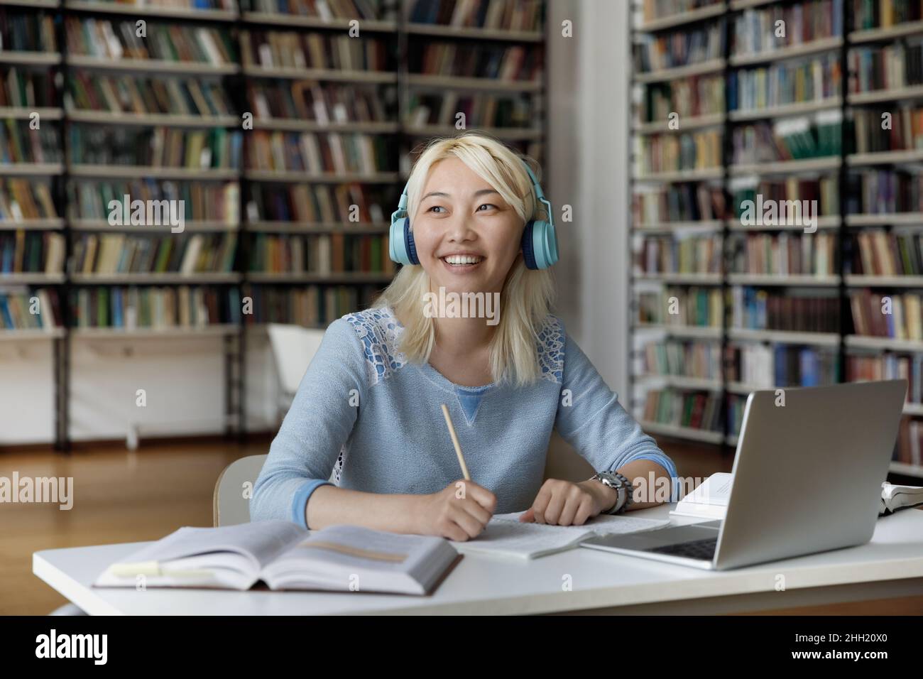 Happy pensive Asian college student girl doing homework Stock Photo - Alamy