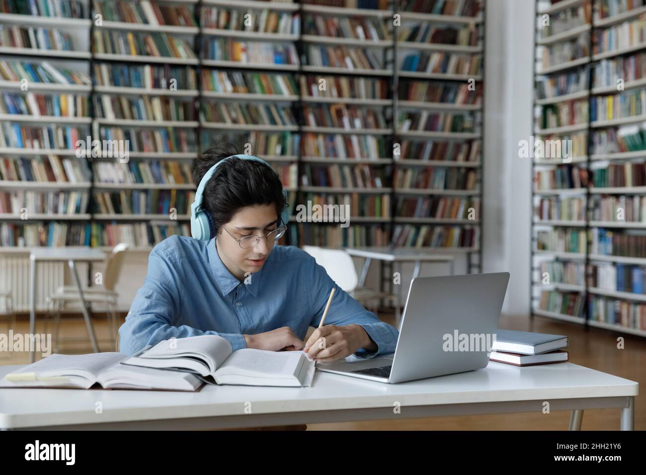 Focused nerdy smart student in glasses and headphones working hard ...