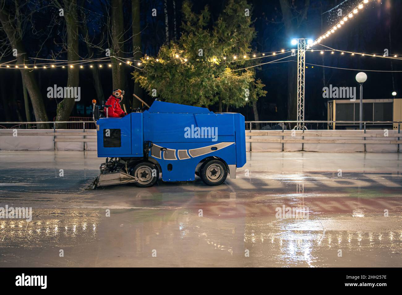 A stadium worker cleans an ice rink on a blue modern ice cleaning ...