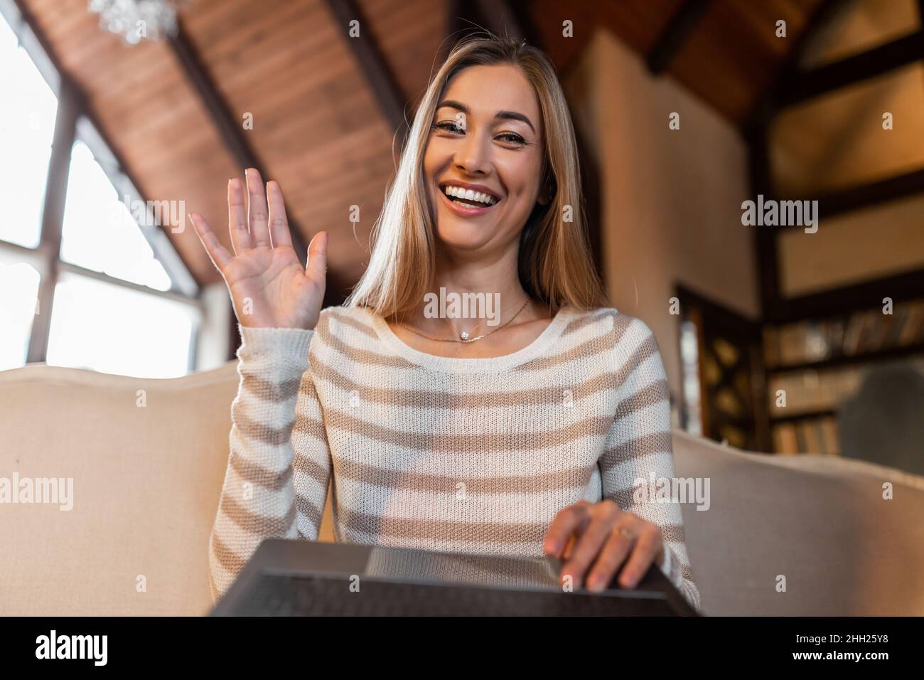 Smiling woman using pc laptop waving hand to camera Stock Photo - Alamy