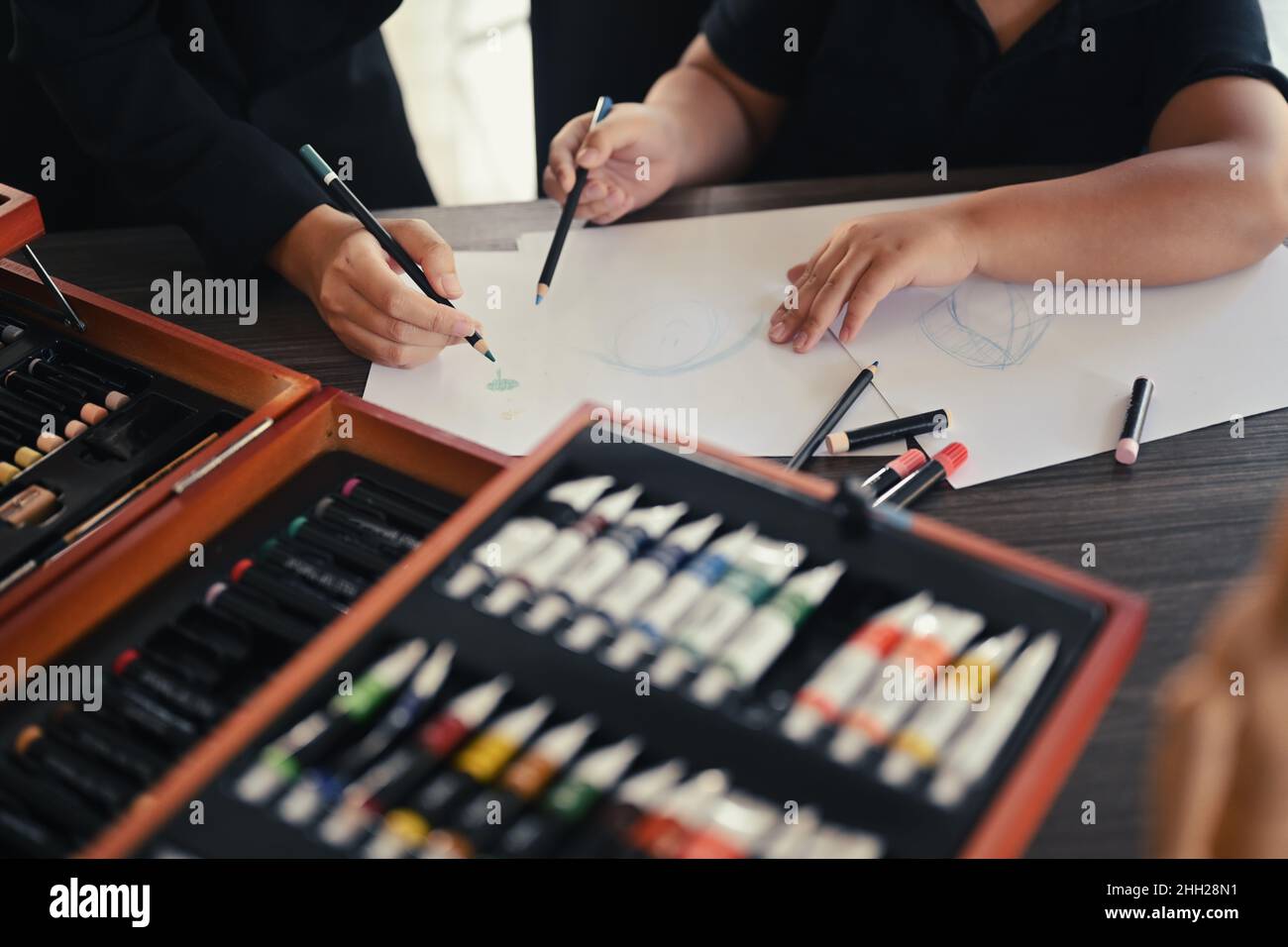 Cropped shot teacher helping children drawing pictures in art class ...