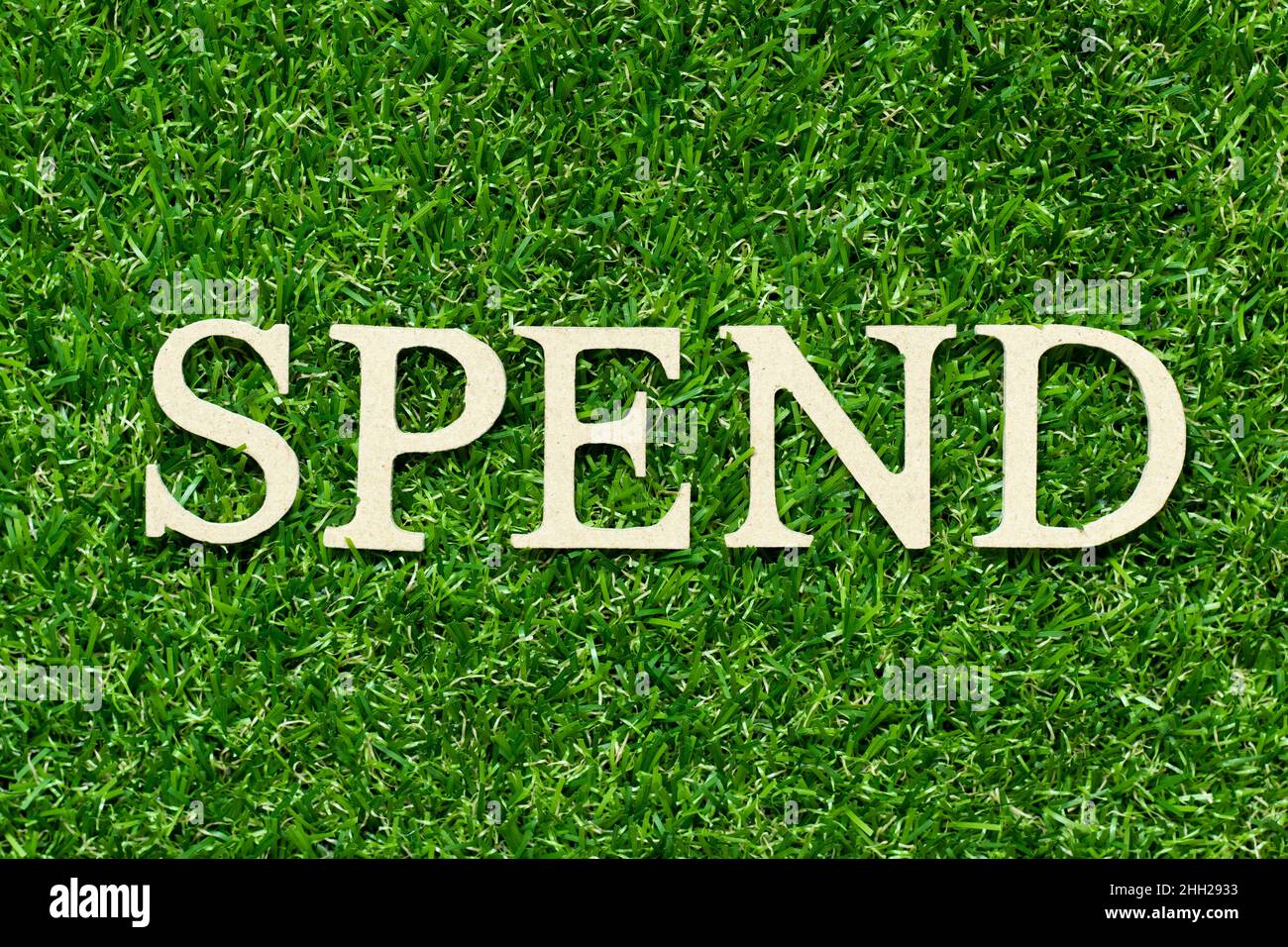 Wood letter in word spend on green grass background Stock Photo - Alamy