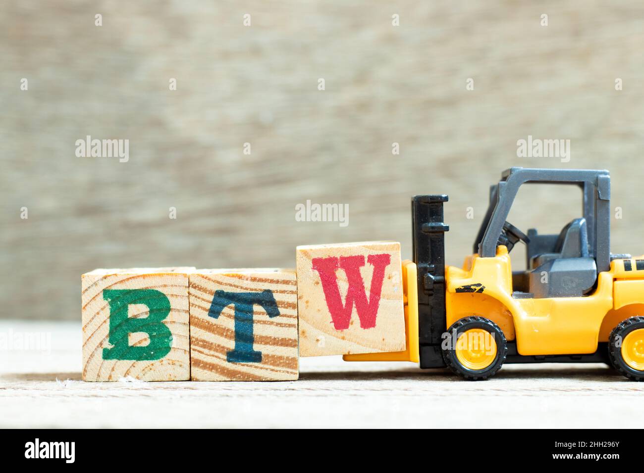 Toy forklift hold letter block W to complete word BTW (Abbreviation of ...