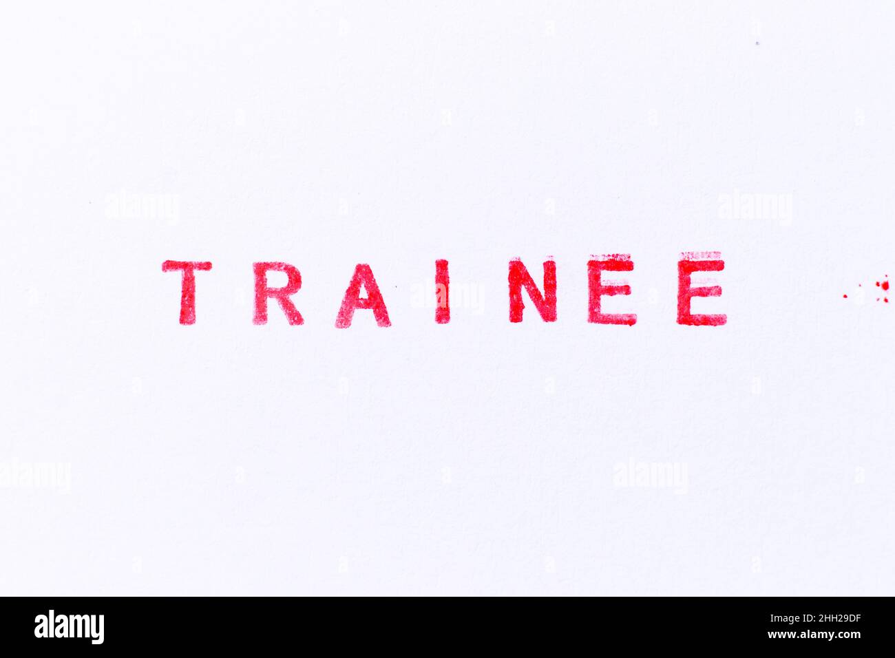 Red color ink rubber stamp in word trainee on white paper background ...