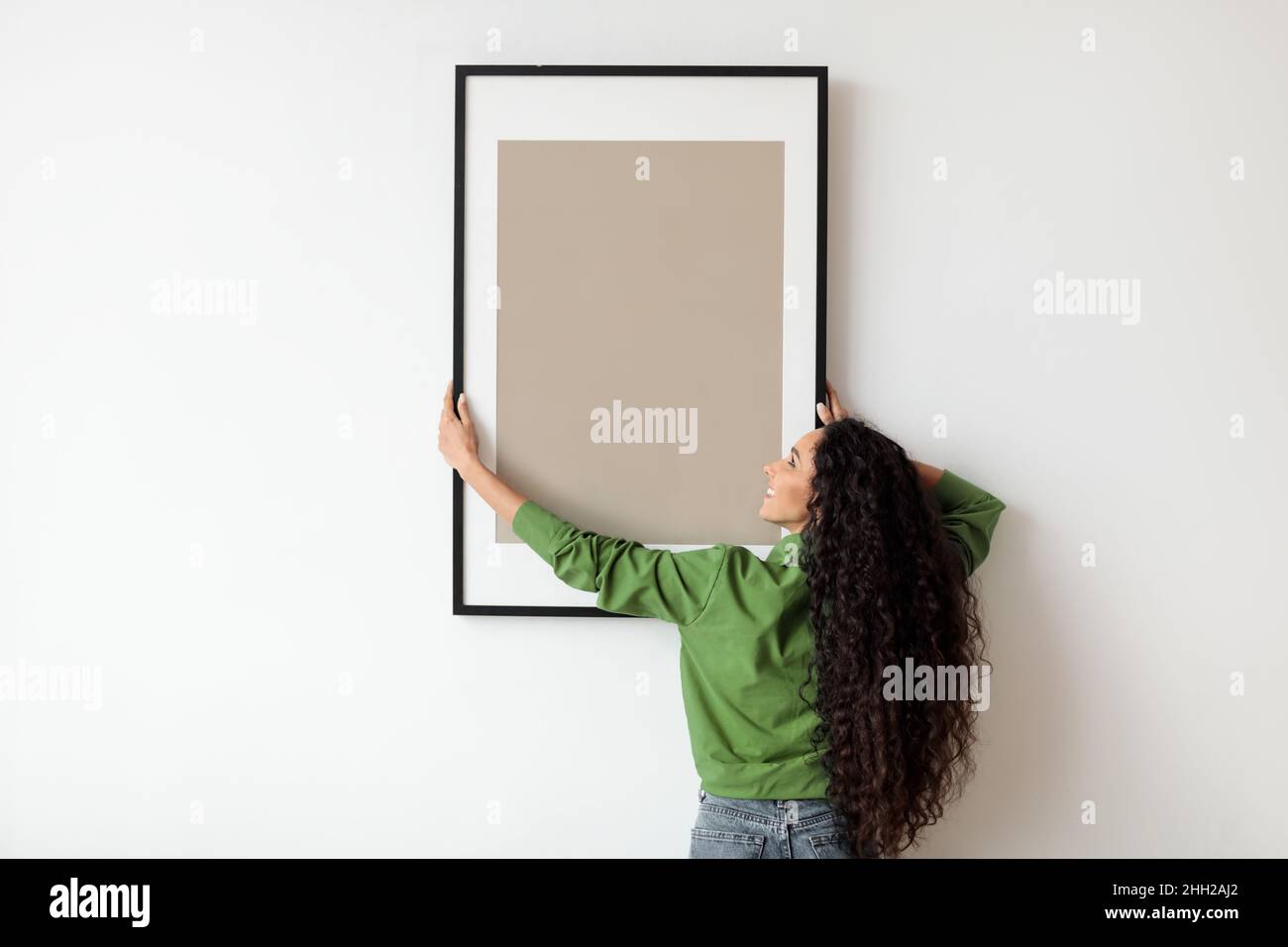 Woman Hanging Frame With Empty Poster On White Wall Indoors Stock Photo ...