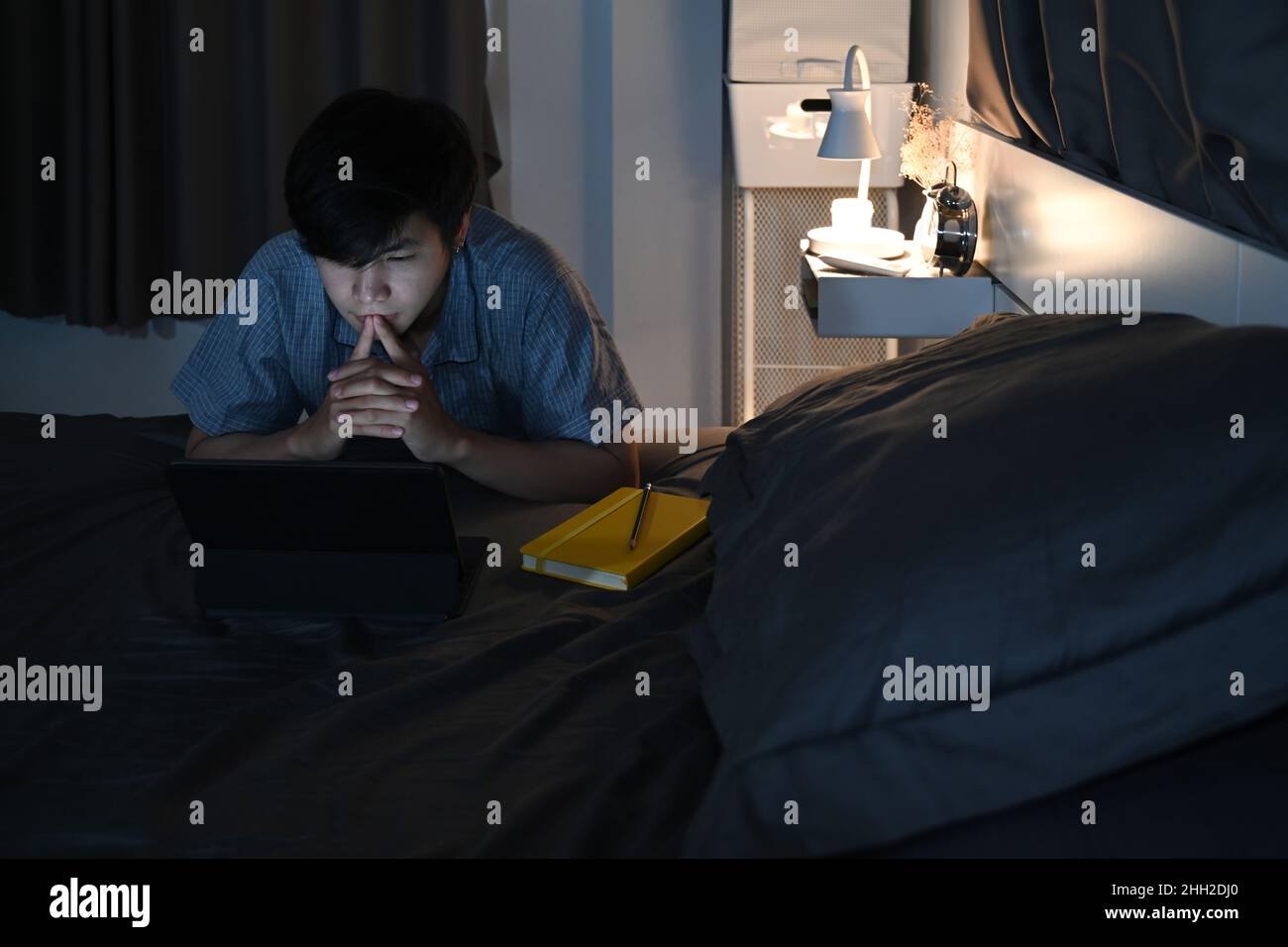 Man sitting in bedroom and using computer tablet at late night Stock ...