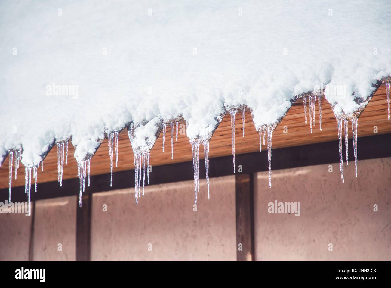Sharp beautiful icicles and melted snow hang from the eaves of the roof ...