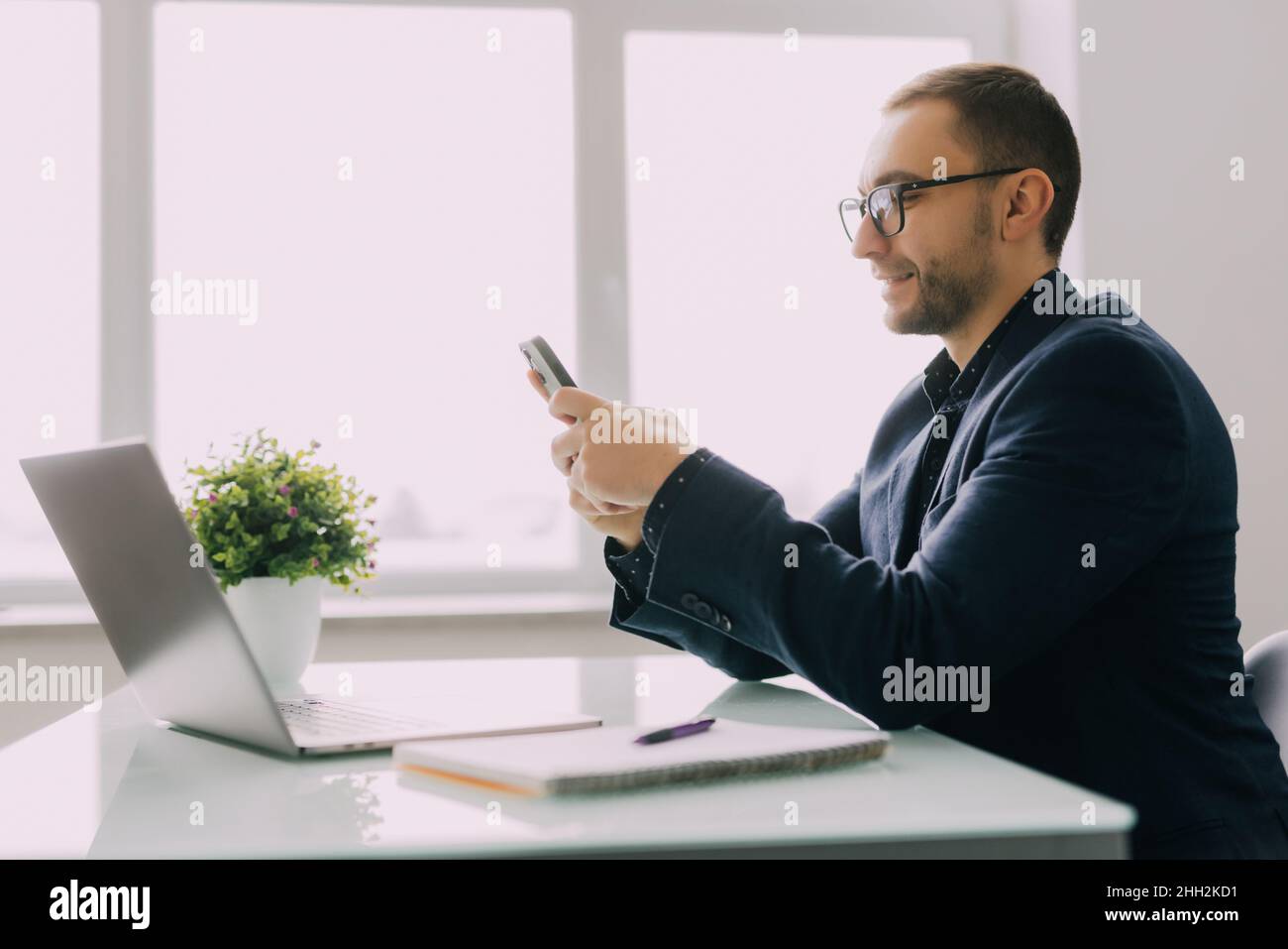 Manager in formal wear holding mobile phone in hands, thinking of ...