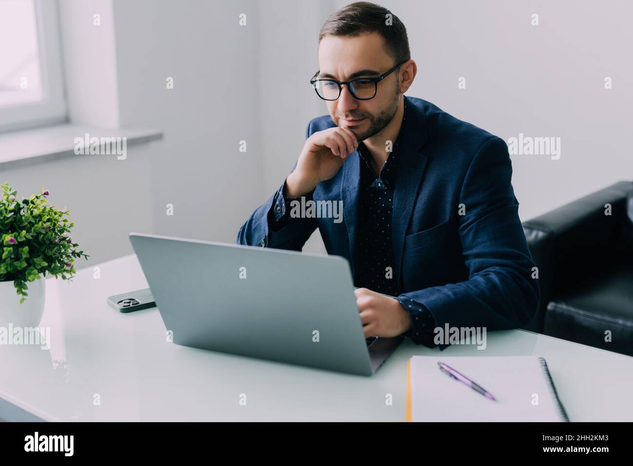 Handsome business executive sitting at his desk in a modern office with ...