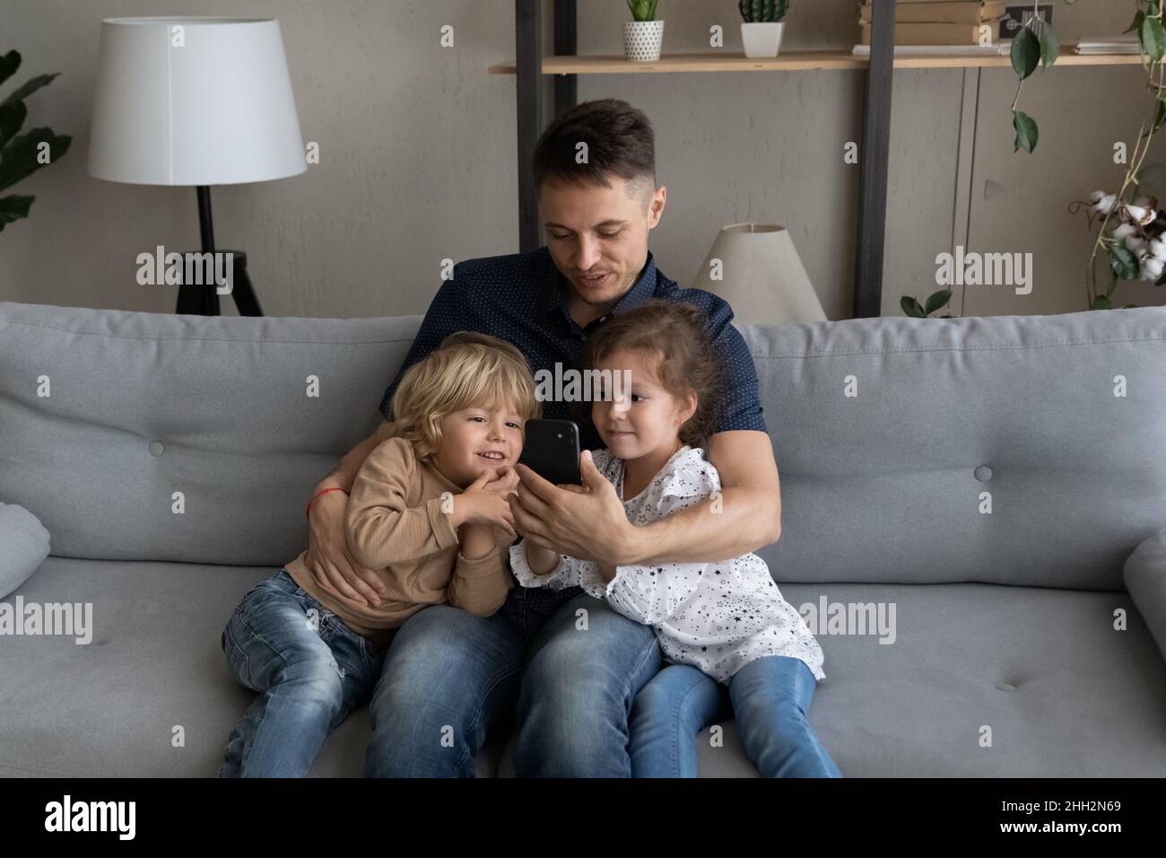 Happy loving young daddy using cellphone with small kids Stock Photo - Alamy